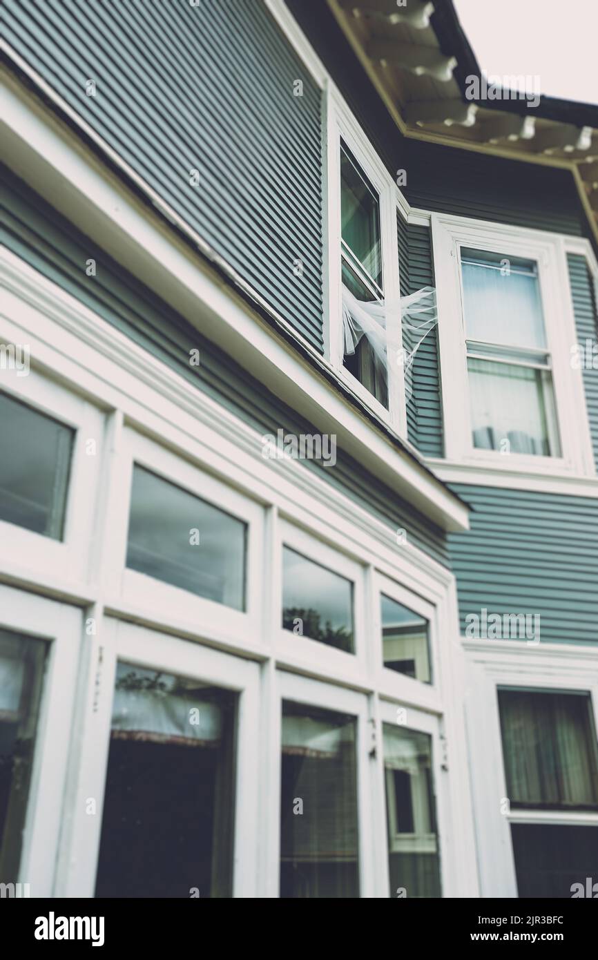 A low angle shot of a curtain blowing out of the window of a house with ...