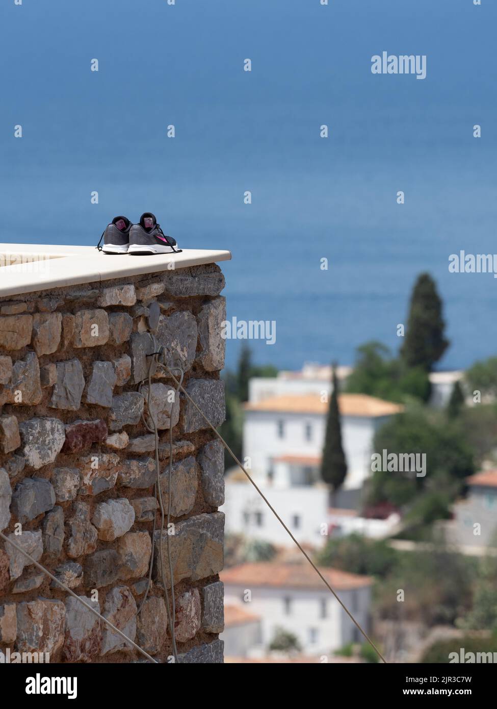 Trainers on villa wall with view over town to Aegean Sea, Hydra, Greece ...