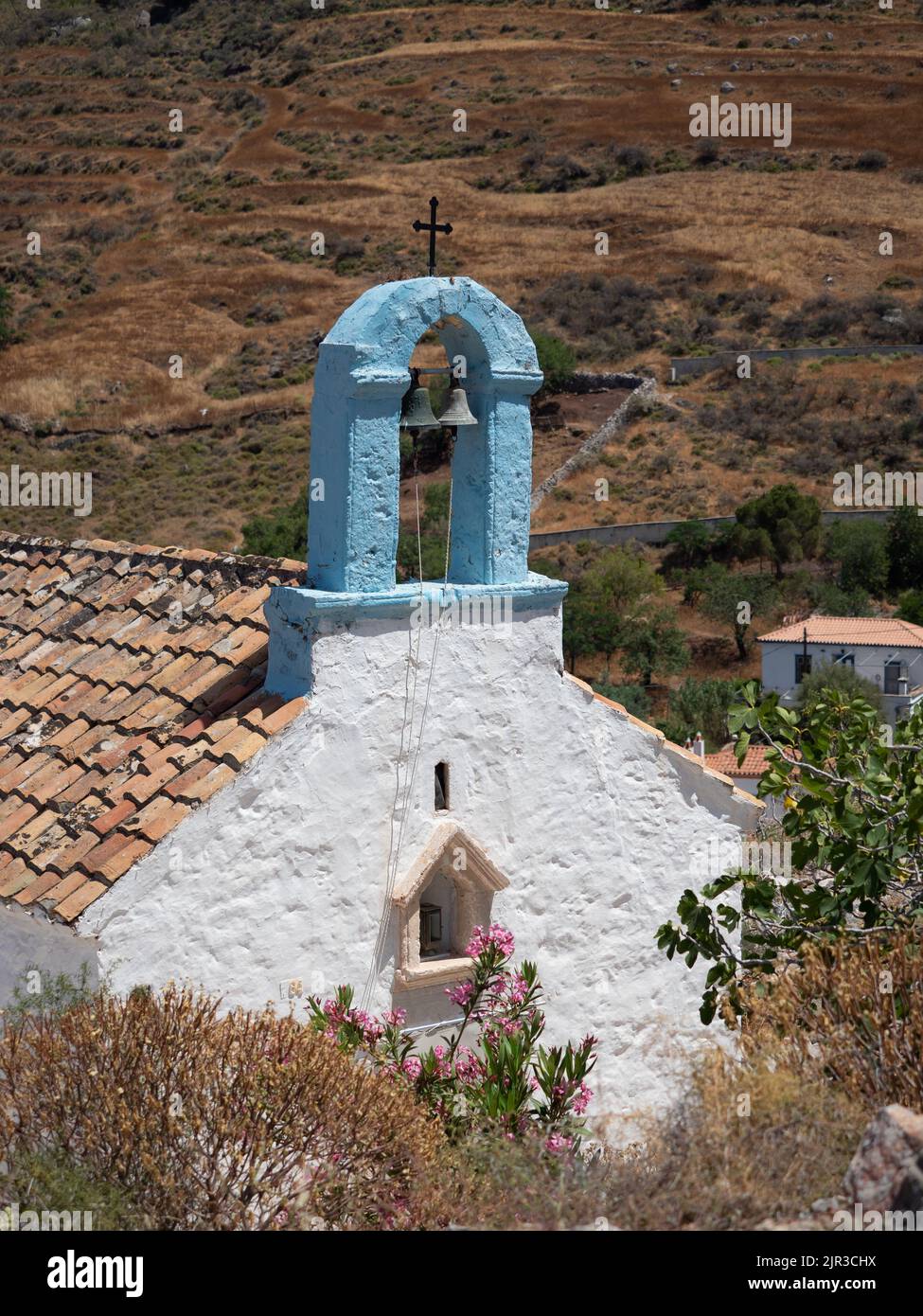 Greek church on an island with pale blue arch, a cross and a bell ...