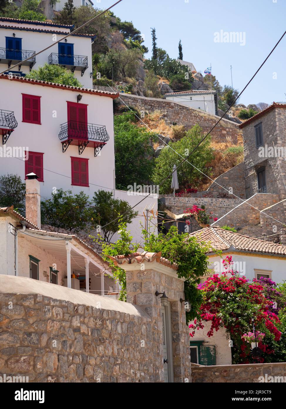 Pretty Greek scene of townhouses and villas with red and blue shutters ...