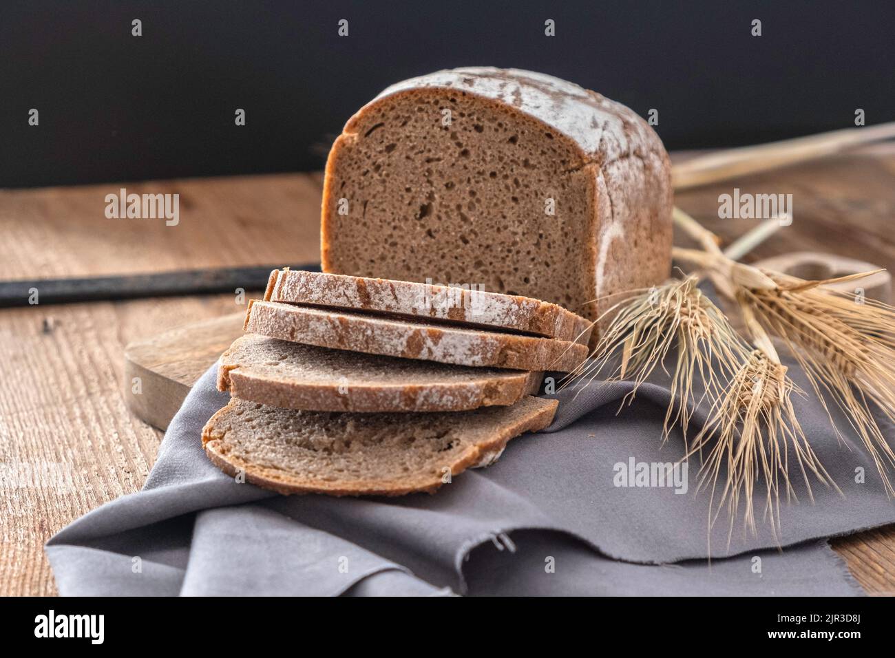 Rye bread lies on a dark wooden board on a light table Stock Photo - Alamy