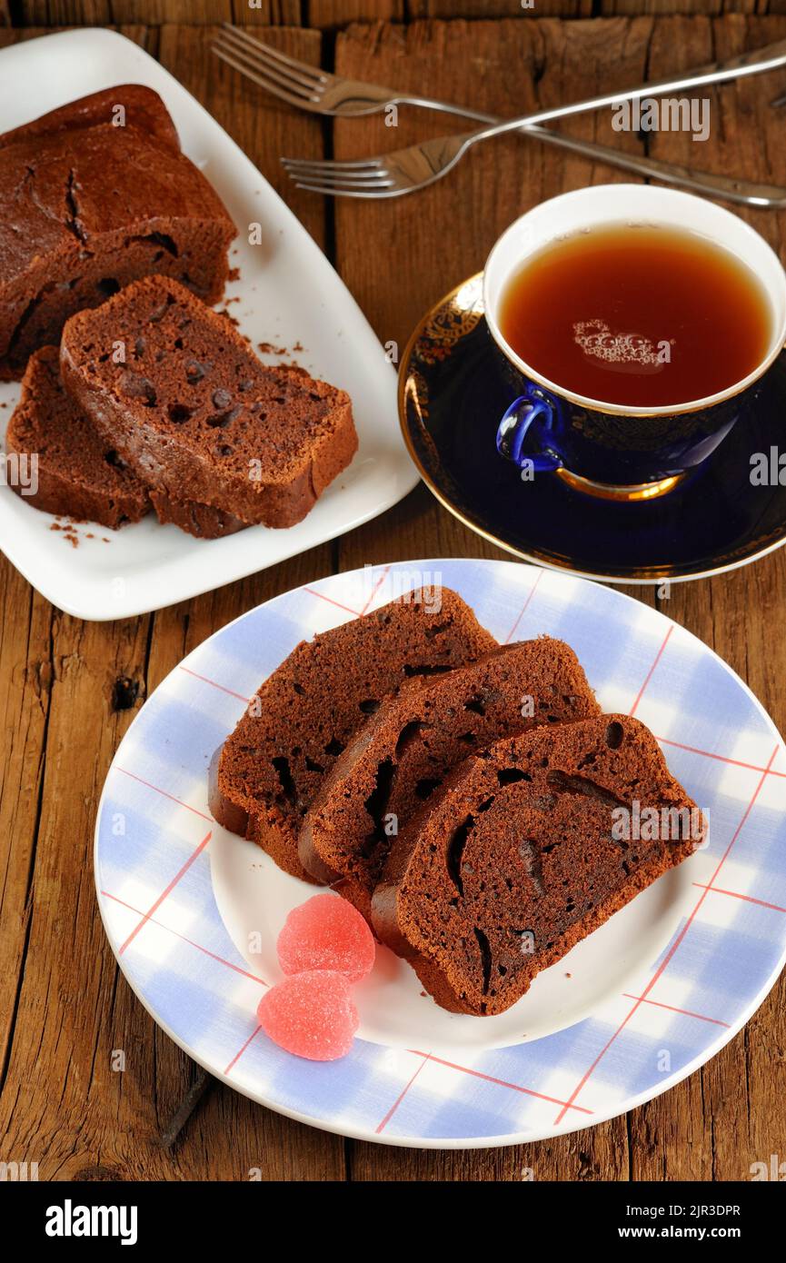 Homemade chocolate cake cut with pink candies and tea in blue cup ...