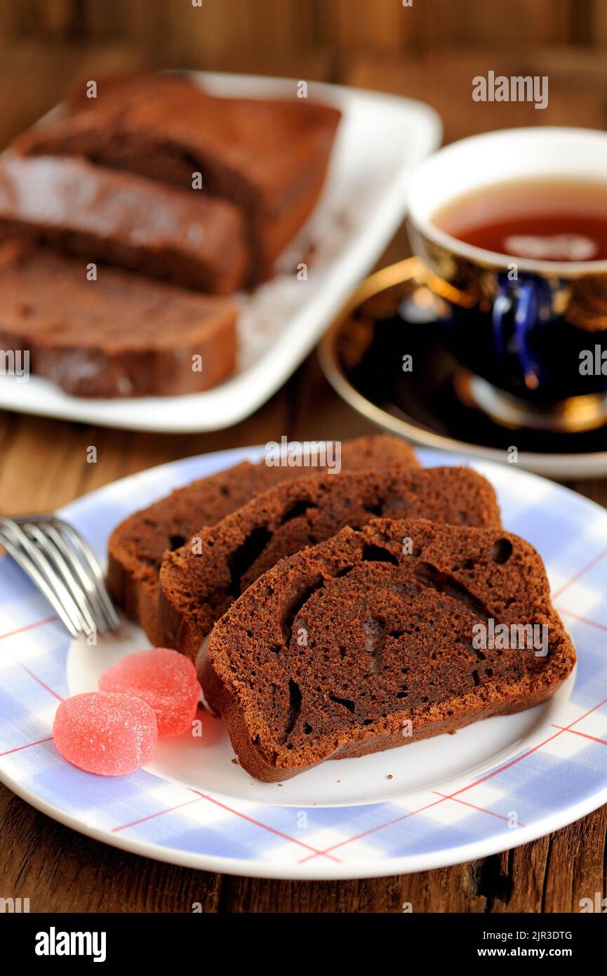 Homemade chocolate cake cut with pink candies and tea in blue cup ...