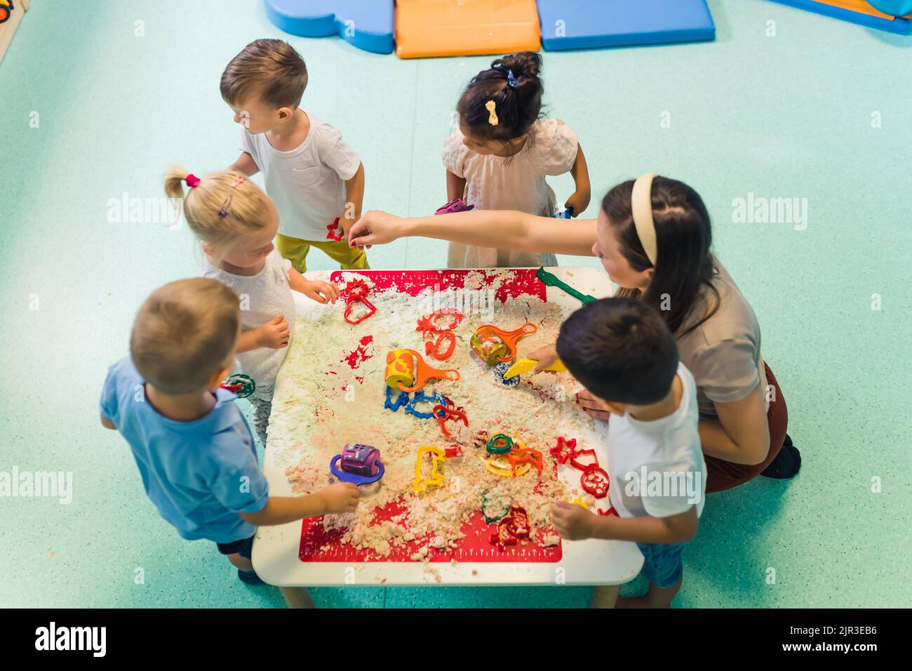 teacher and kids playing with kinetic sand in the kindergarten. High ...