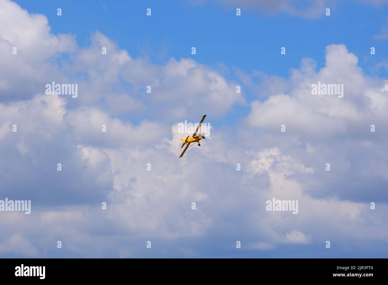 Single engine yellow propeller air plane flying at cloudy blue sky in a ...