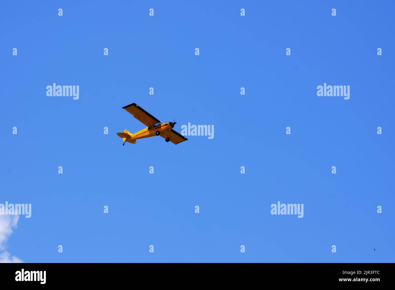 Single engine yellow air plane flying close to the ground level in a ...