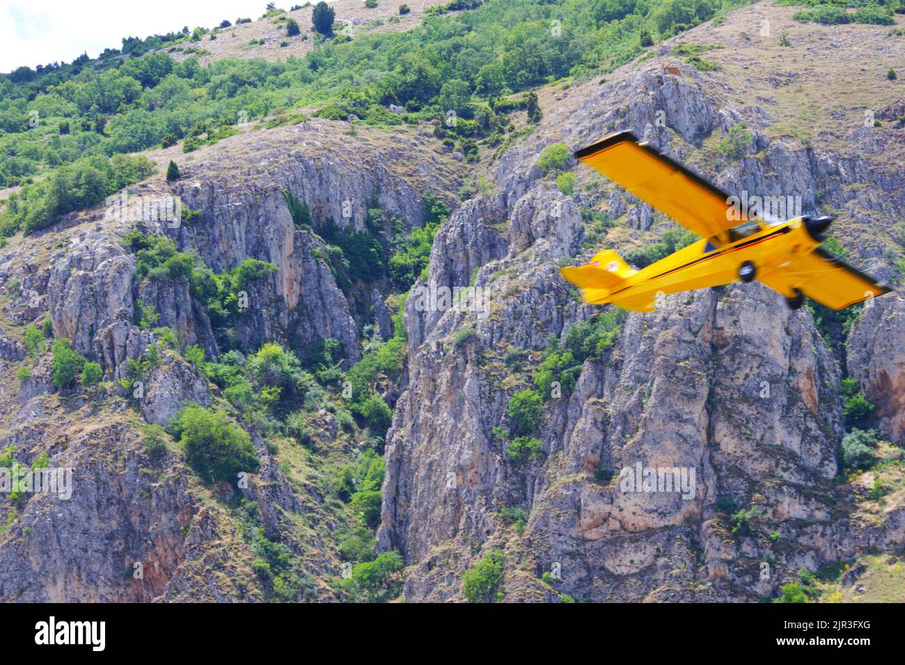 Single engine yellow air plane flying close to the ground, just above ...