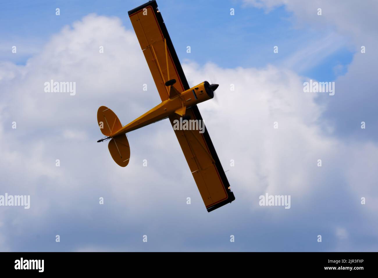Single engine yellow propeller air plane flying at cloudy blue sky in a ...