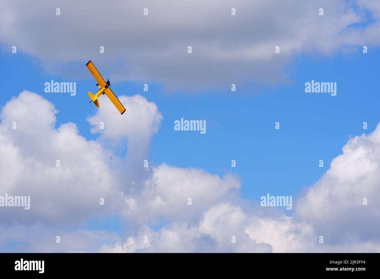 Single engine yellow propeller air plane flying at cloudy blue sky in a ...