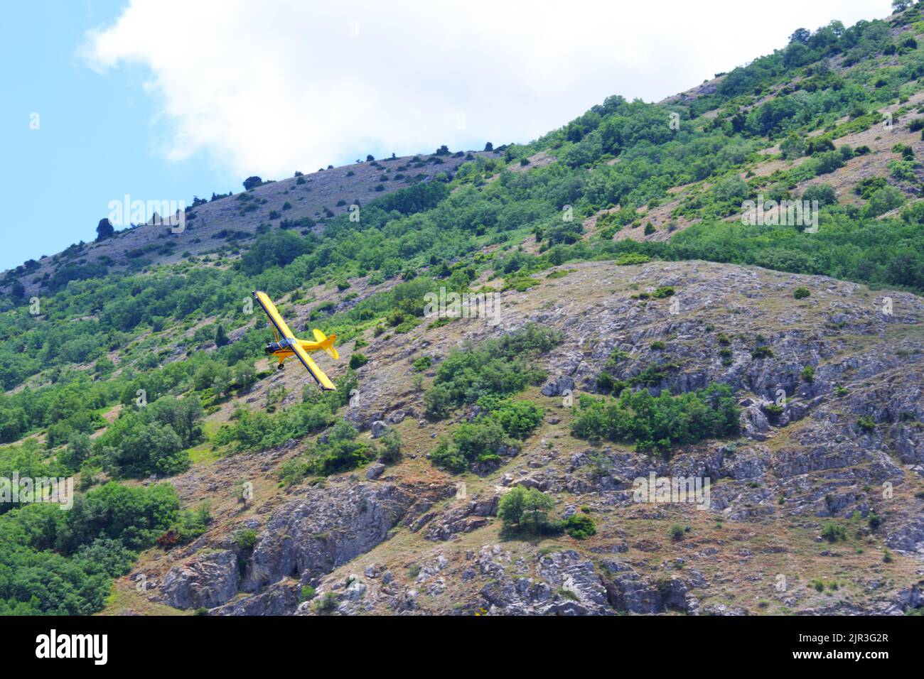 Single engine yellow air plane flying close to the ground, just above ...