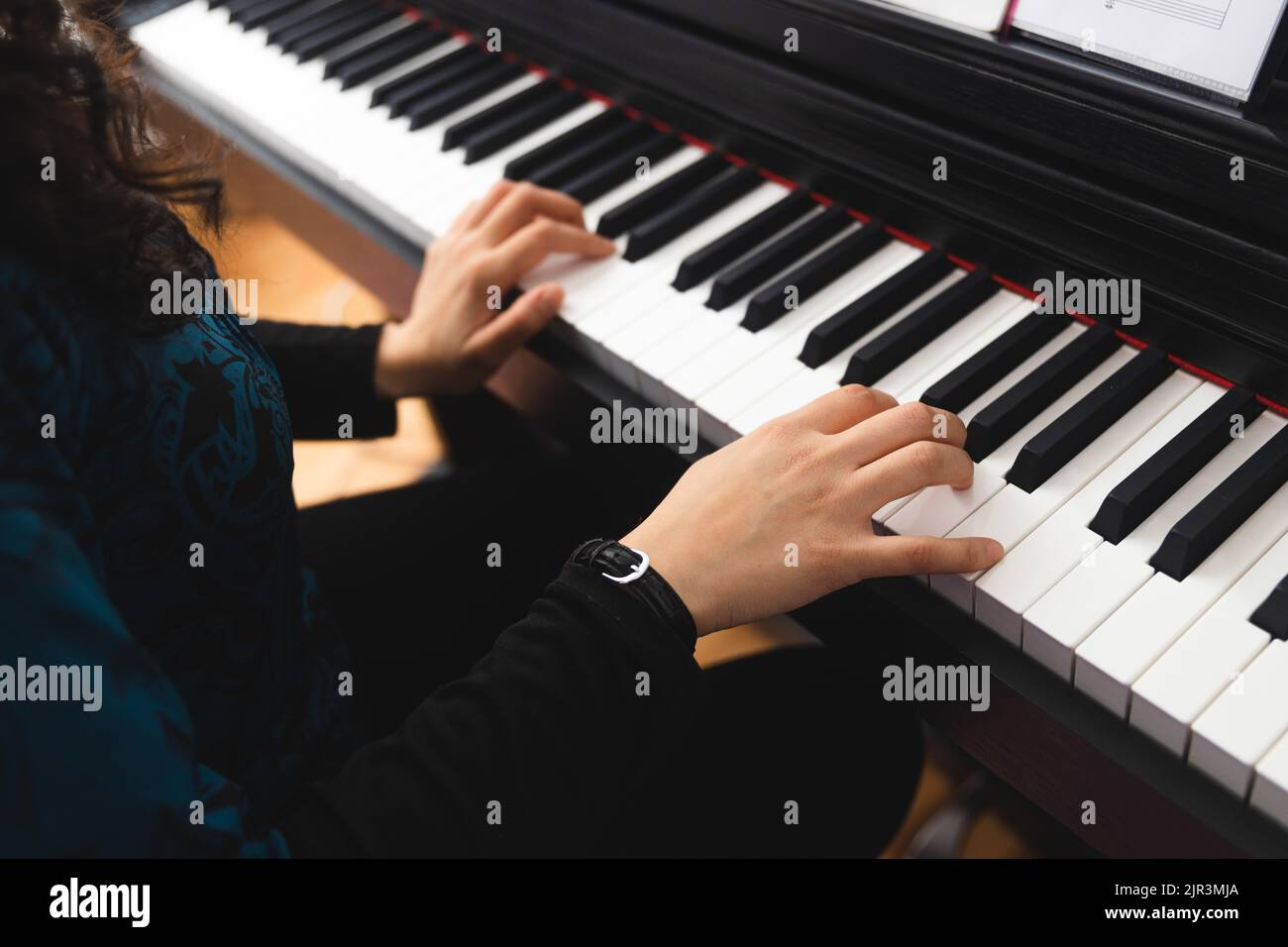 Close up of woman's hands playing piano by reading sheet music ...