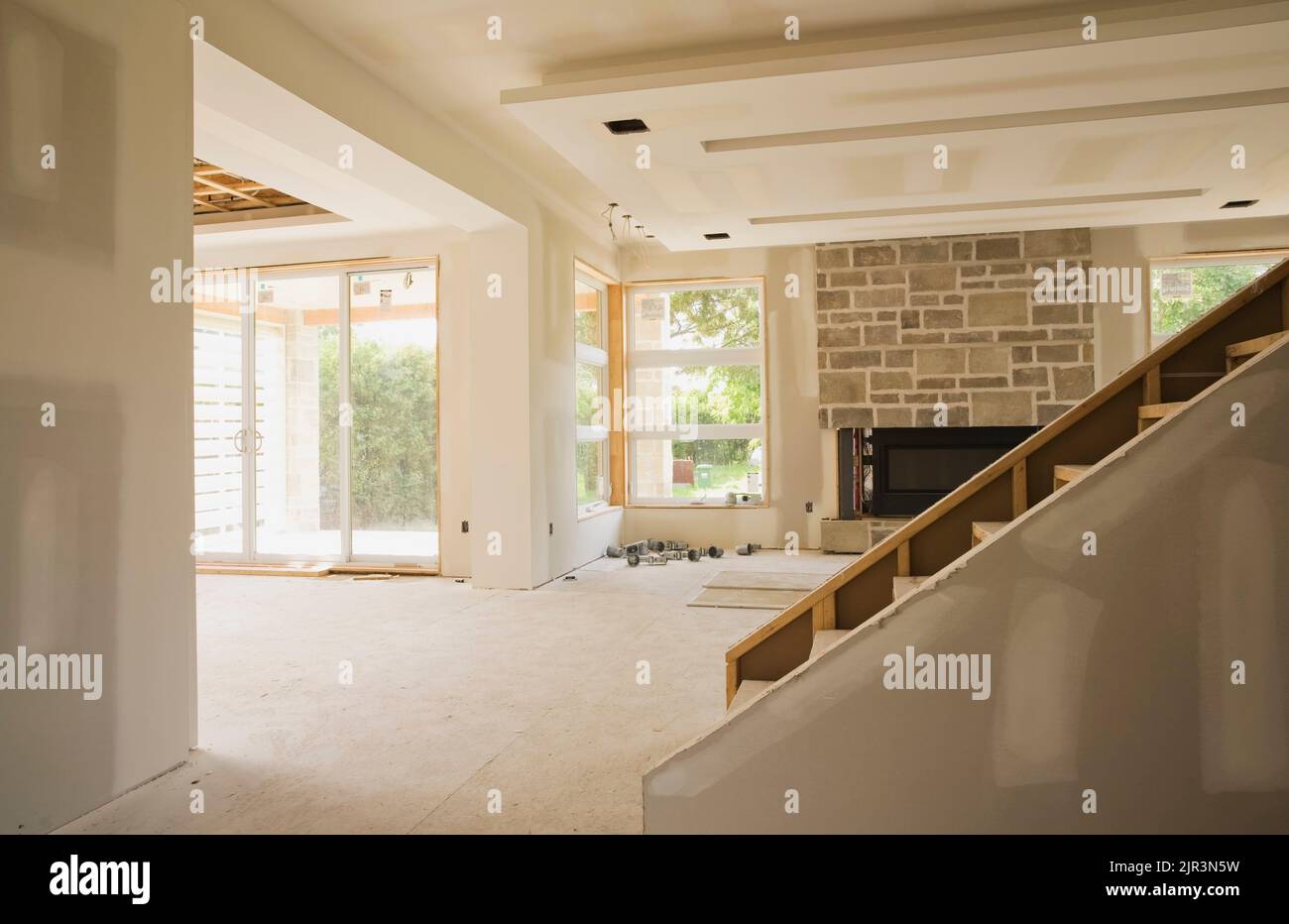 Unfinished staircase and unpainted drywall in living room inside ...
