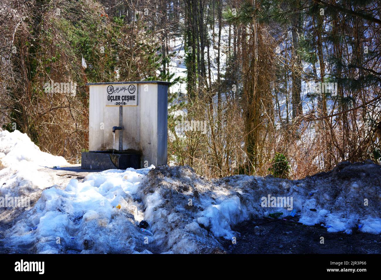 Marble public fountain at a forest in mountain within trees. Snowy ...