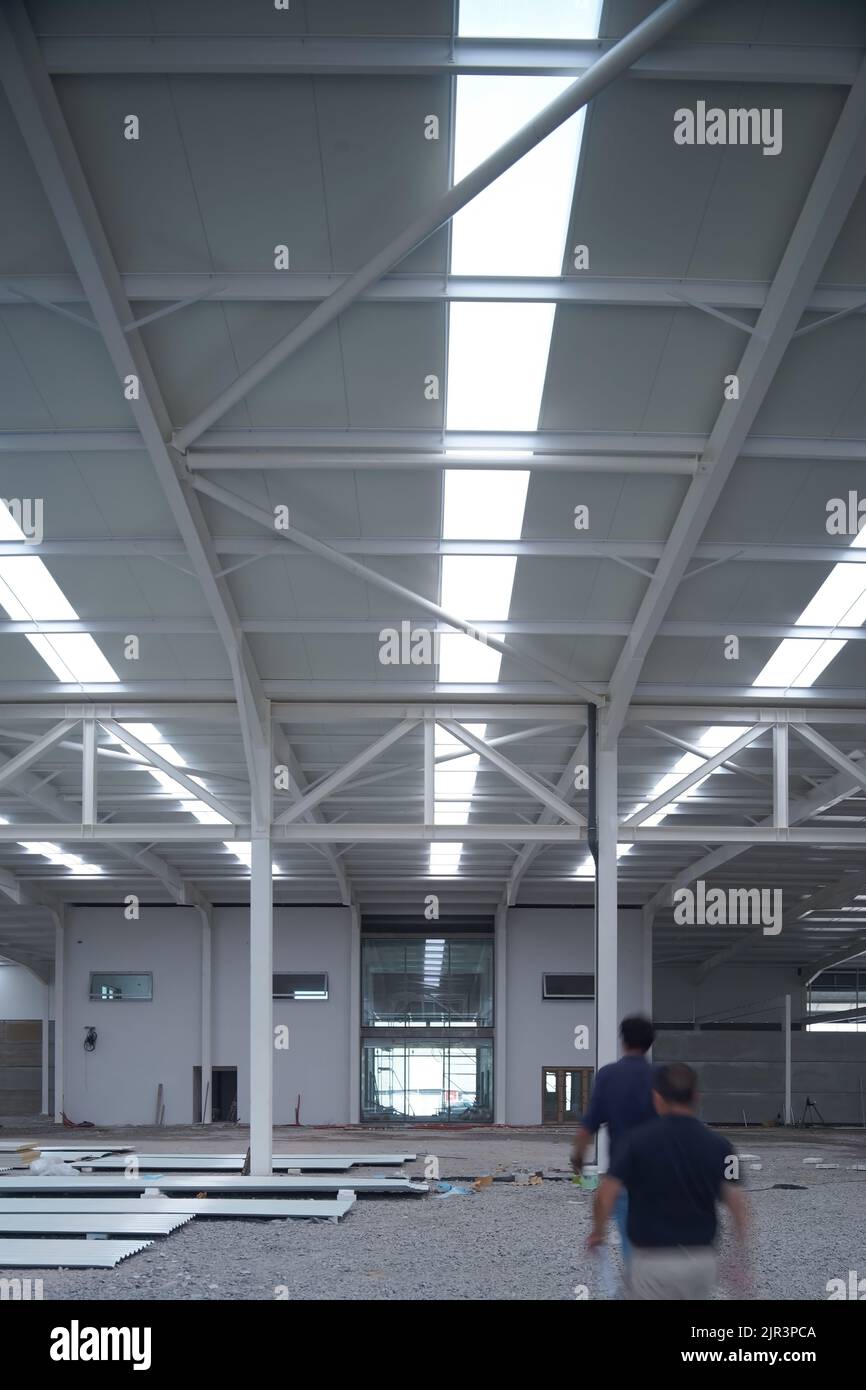two people walking, in an industrial building repair, all white, steel ...
