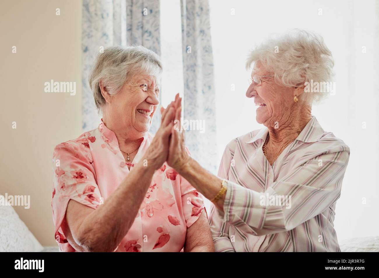 Good friends make for a good mood. two happy elderly women giving each ...