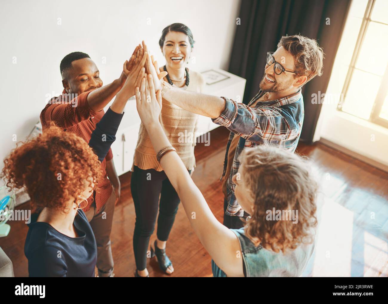 We celebrate our achievements together. creative employees giving each other a high-five in the ...