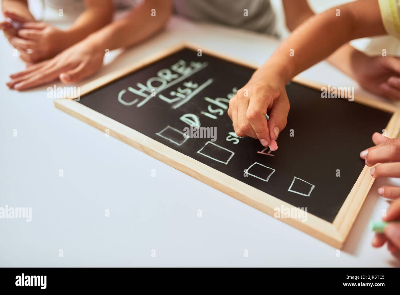 Making a note of their chores for the day. Closeup shot of kids writing ...