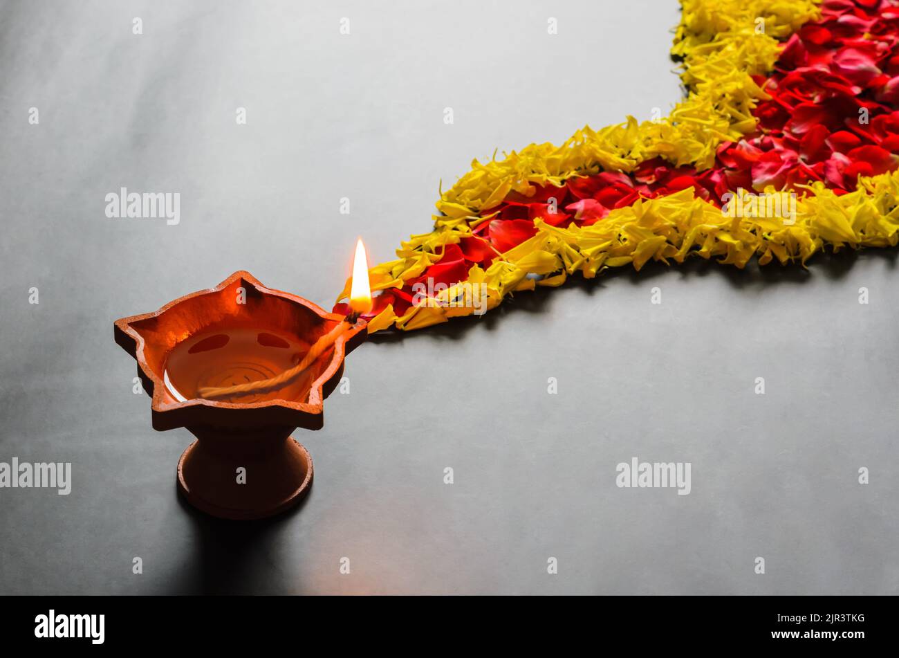Clay diya lamp with decorative marigold and rose flower petals rangoli ...