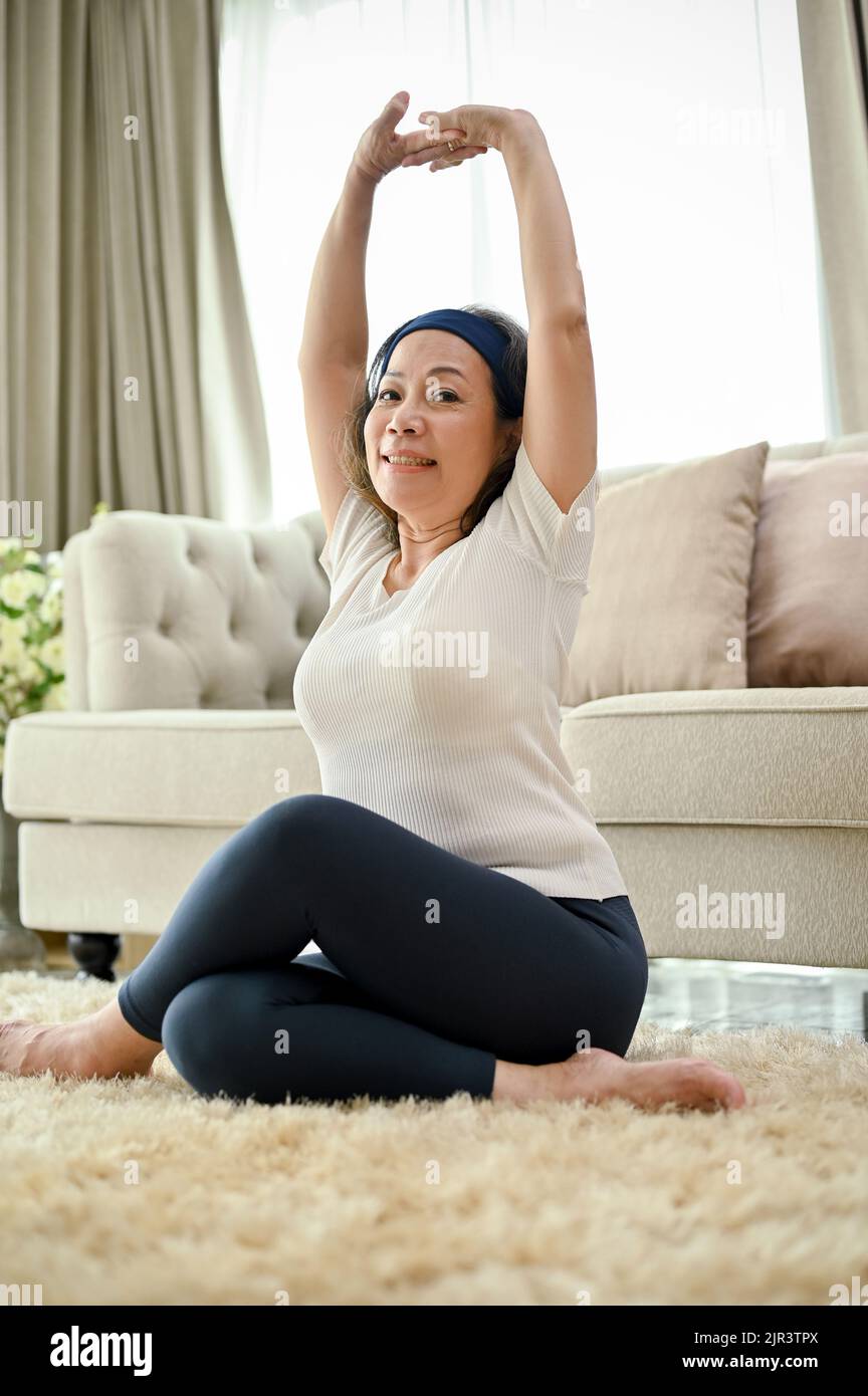 Portrait, Relaxed and calm Asian-aged woman practicing yoga in her ...