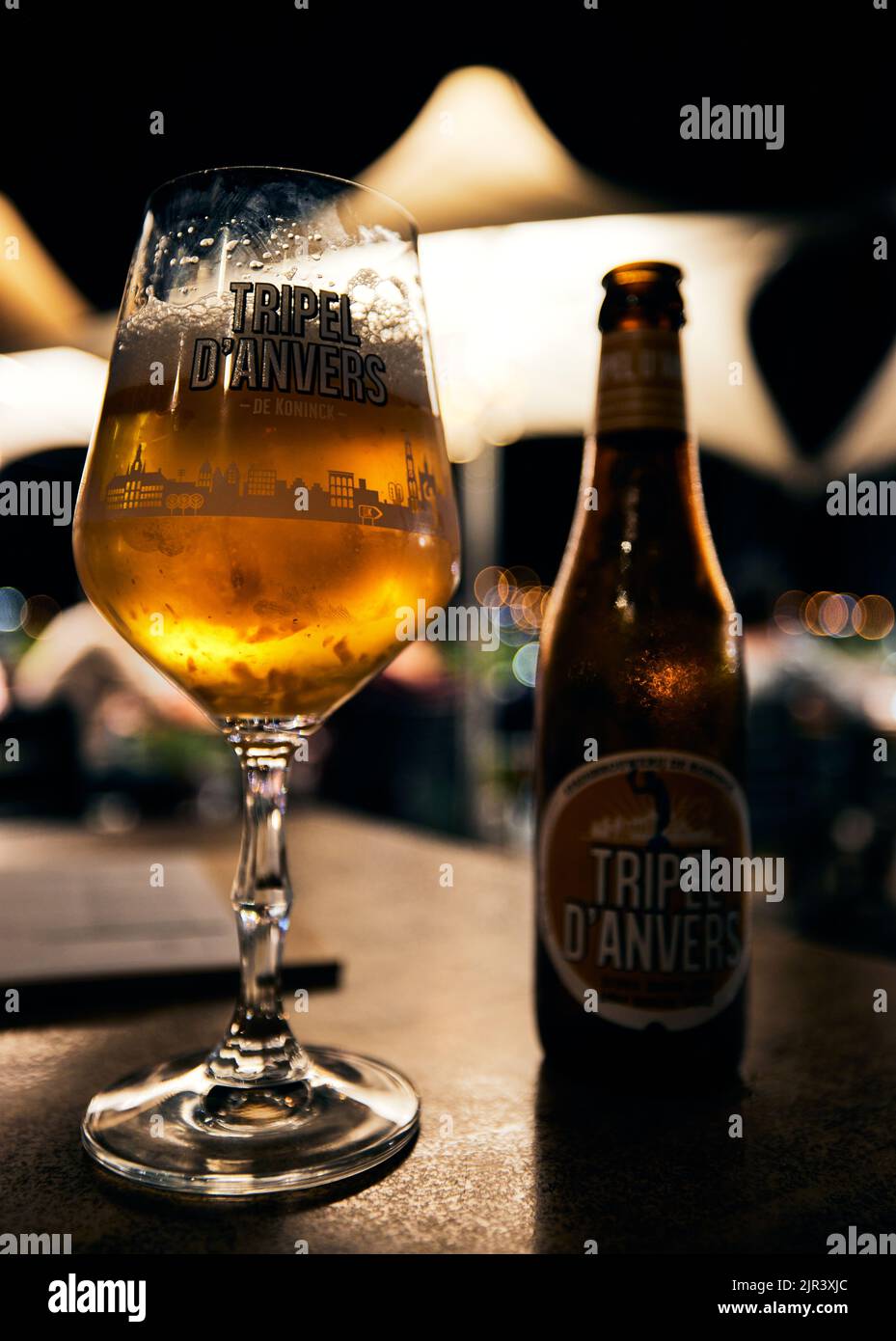A vertical shot of a glass and bottle of beer on a table in a bar in ...