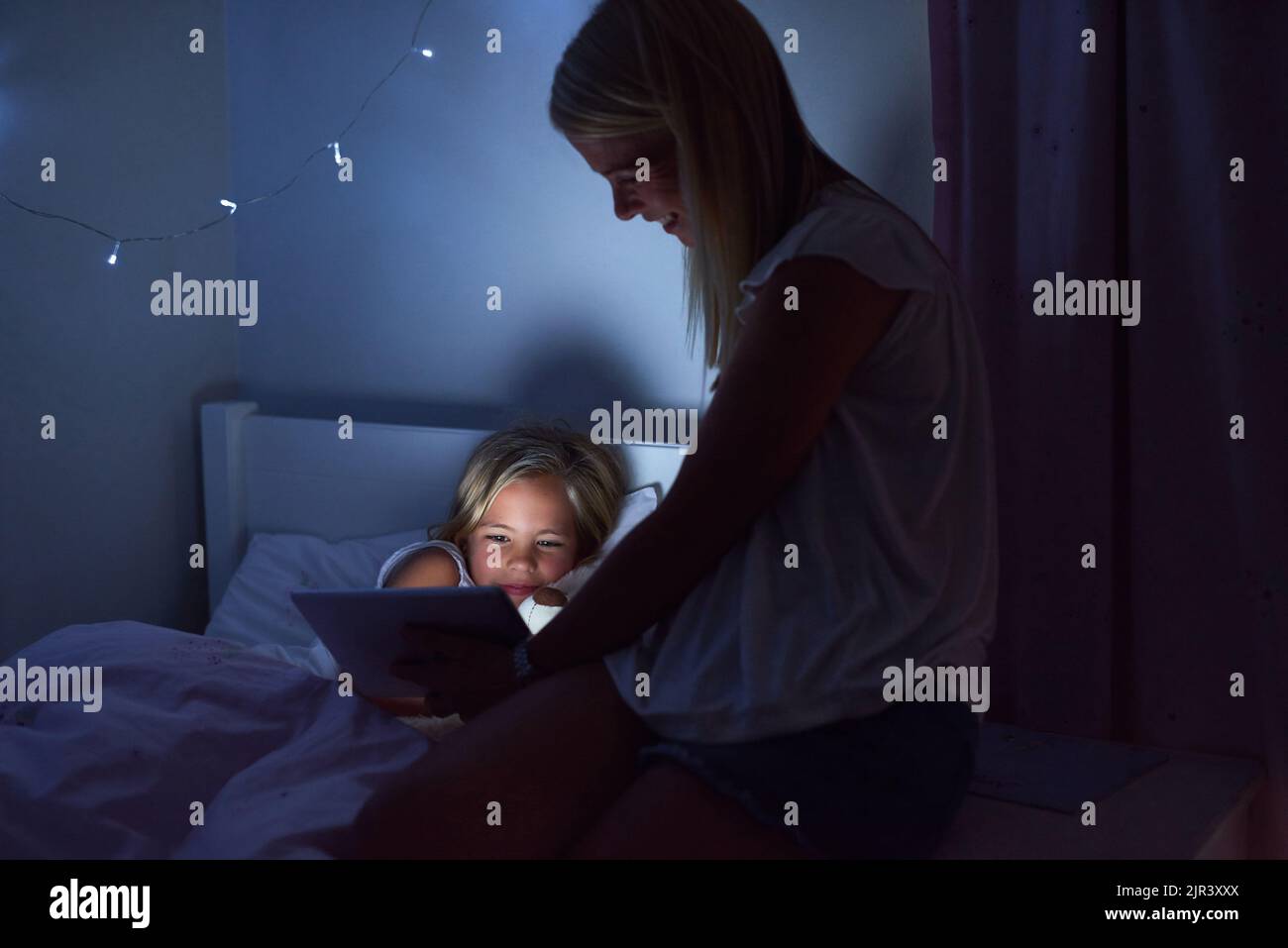 Just one more story. a little girl and her mother using a digital ...
