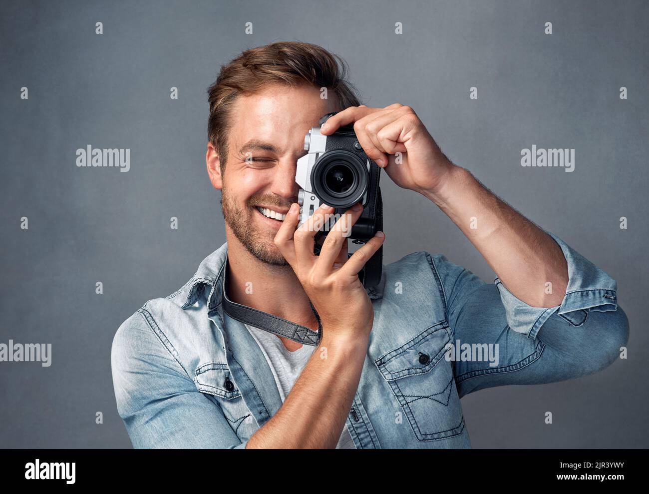Seeing life through a lens. Portrait of a happy young man holding up a ...