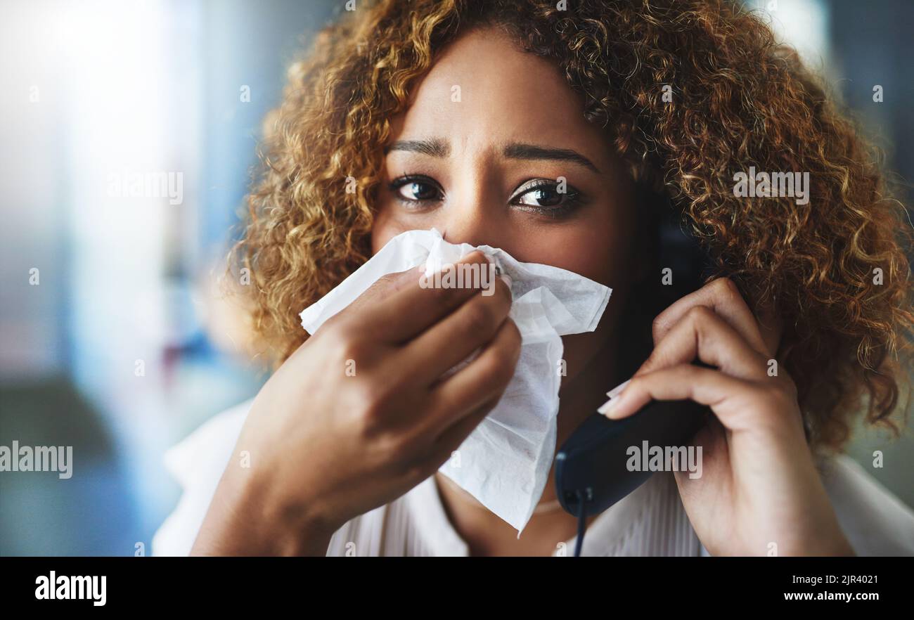 Someone call a doctor. a frustrated businesswoman blowing her nose and ...