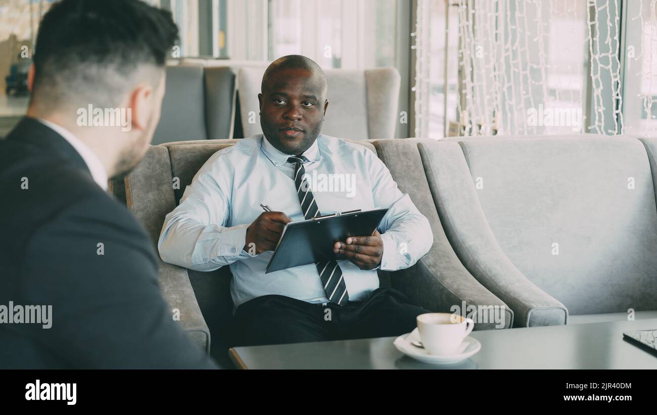 African american HR manager having job interview with young man in suit ...