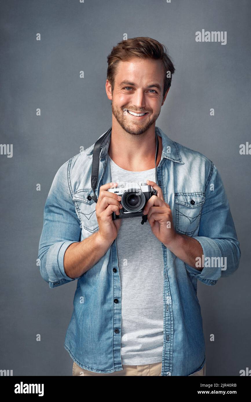 Capturing life through a lens. Portrait of a happy young man holding up ...