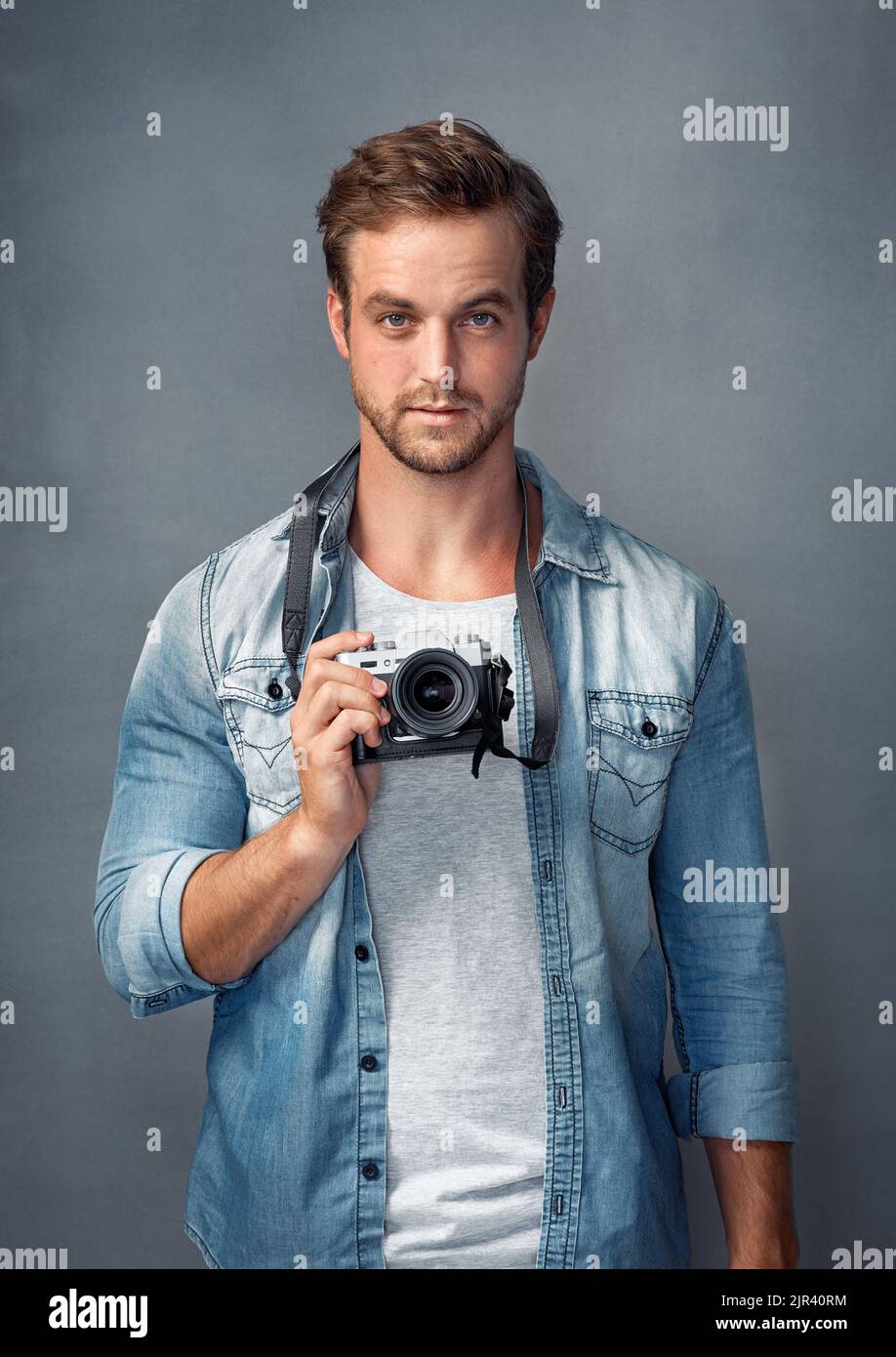 I dont miss a moment. Portrait of a happy young man holding up a camera ...