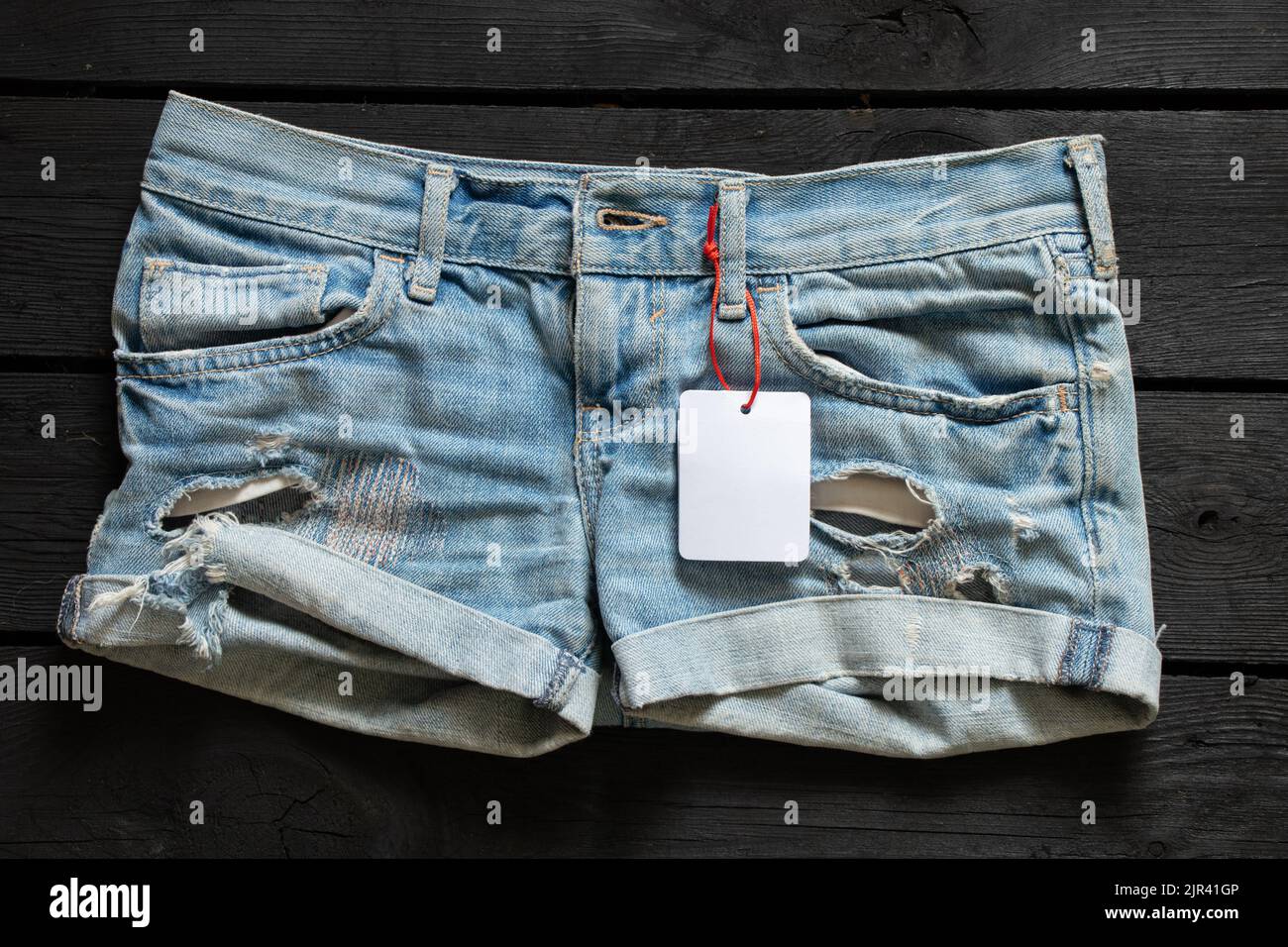 womens denim shorts with white blank paper price tag for text on table ...