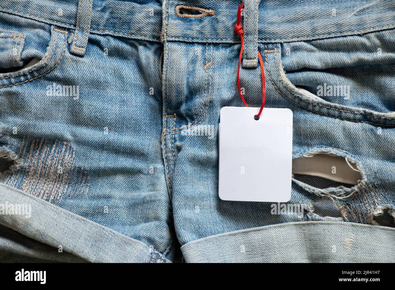 womens denim shorts with white blank paper price tag for text on table ...