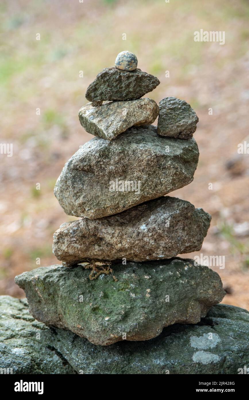 A vertical view of stones balancing on top of each other on a blurred ...