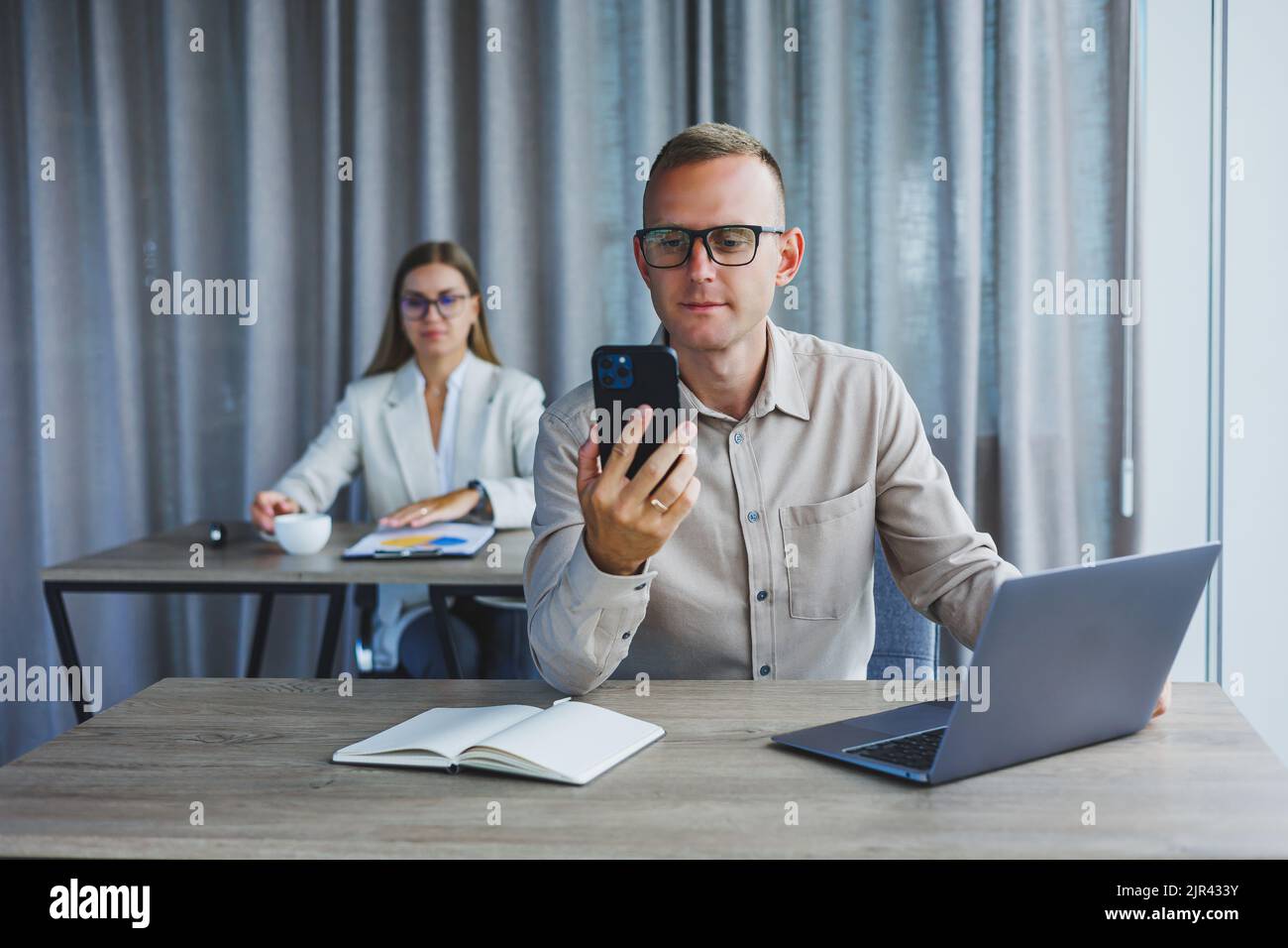 A male manager is talking on a mobile phone while sitting at a table ...