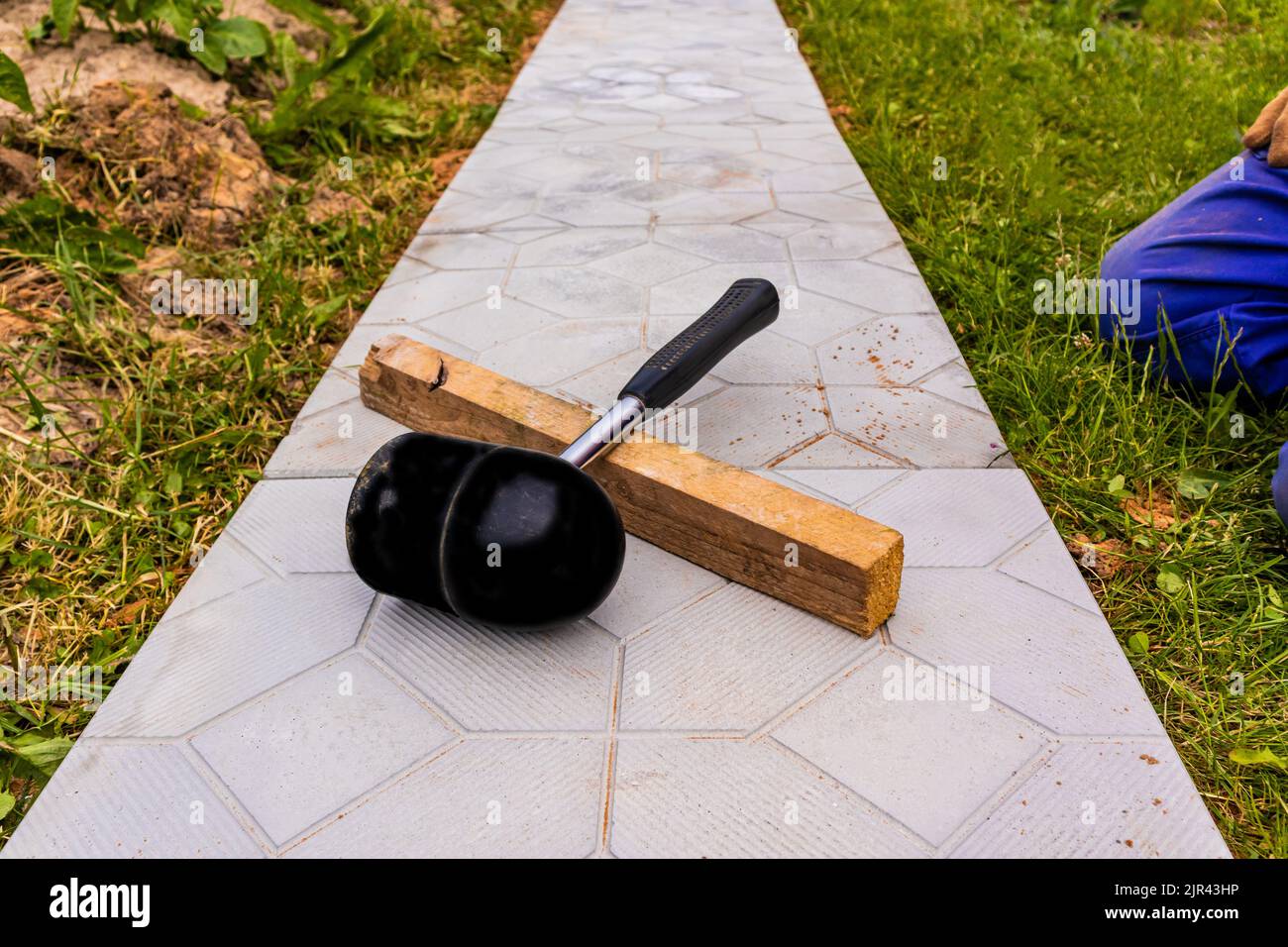a tool for laying a garden path with stone tiles lies on the finished ...