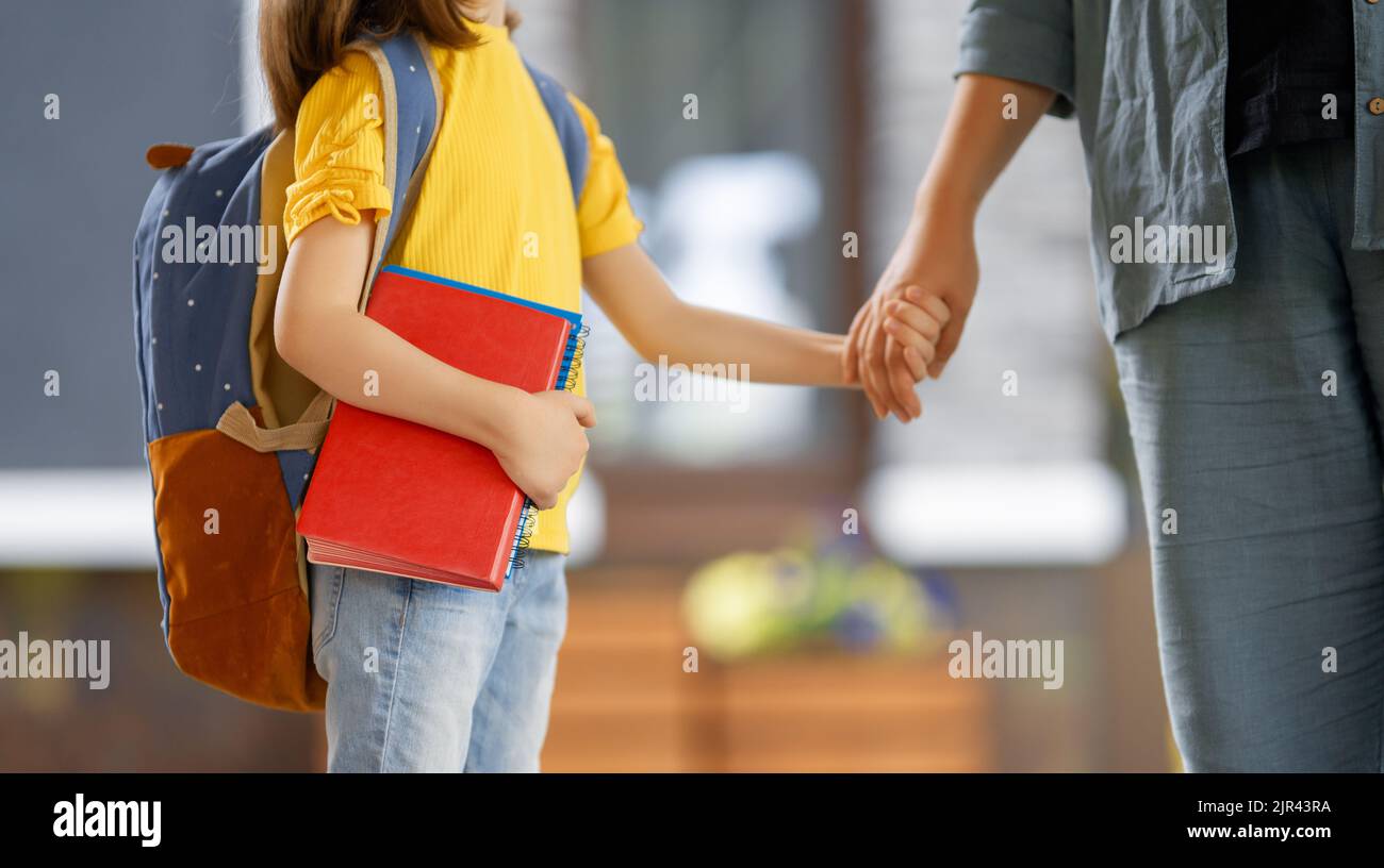 Parent and pupil of primary school going hand in hand. Woman and girl ...