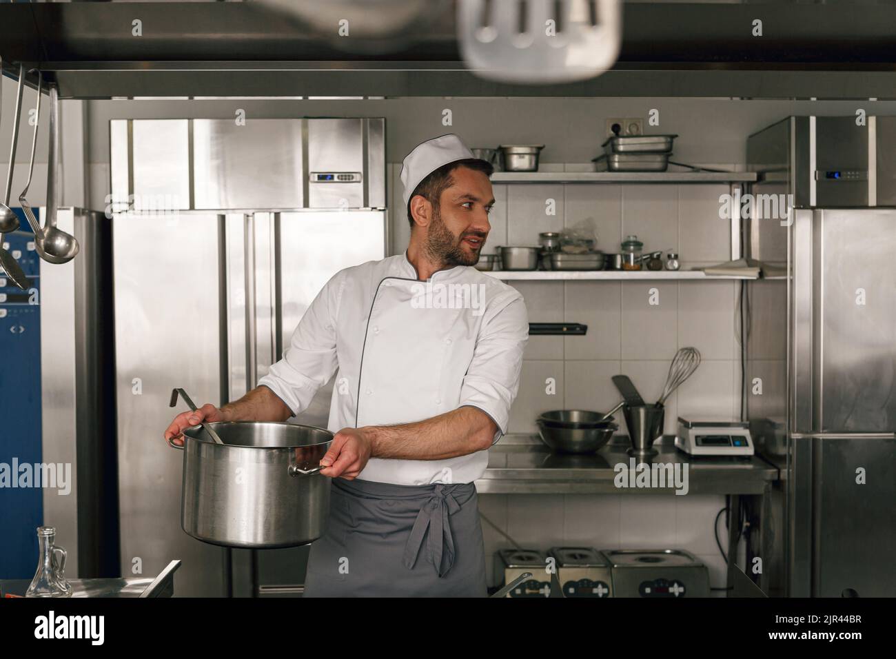 Chef cooking tasty dish in kitchen of restaurant using modern equipment ...