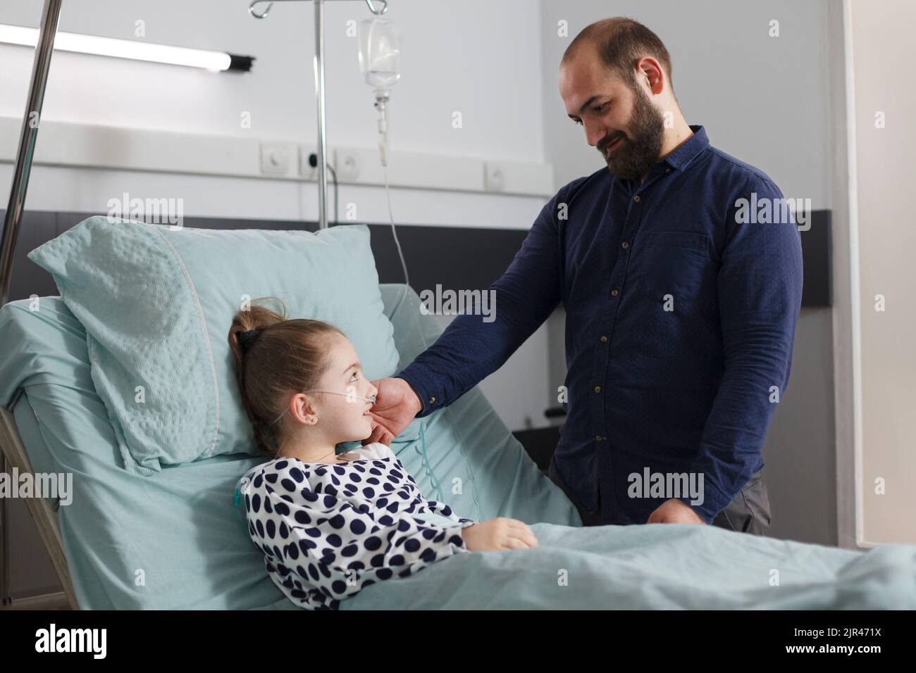 Loving father comforting hospitalized sick daughter resting in patient ...