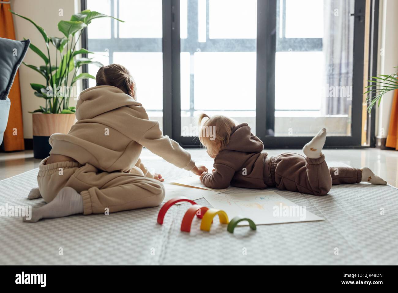 Little caucasian siblings drawing together on floor in living room at ...