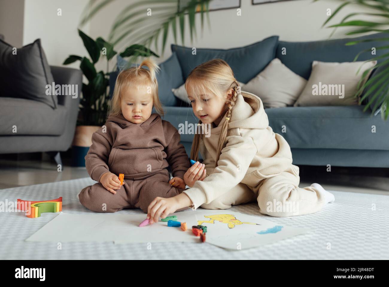Little caucasian siblings drawing together on floor in living room at ...