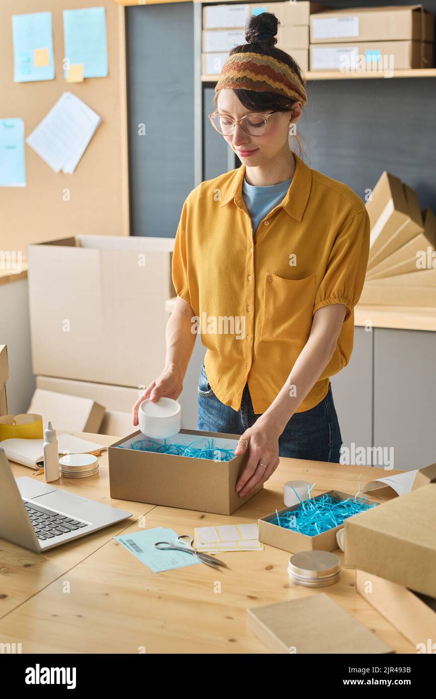 Worker putting packed products in cardboard boxes before export or ...