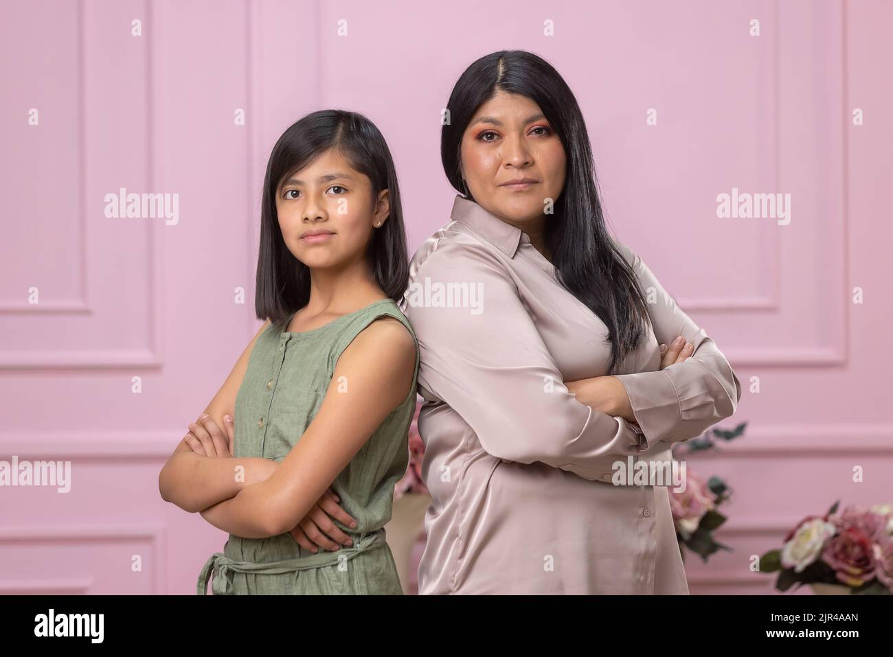 A Hispanic mother with her daughter posing confidently on a pink ...