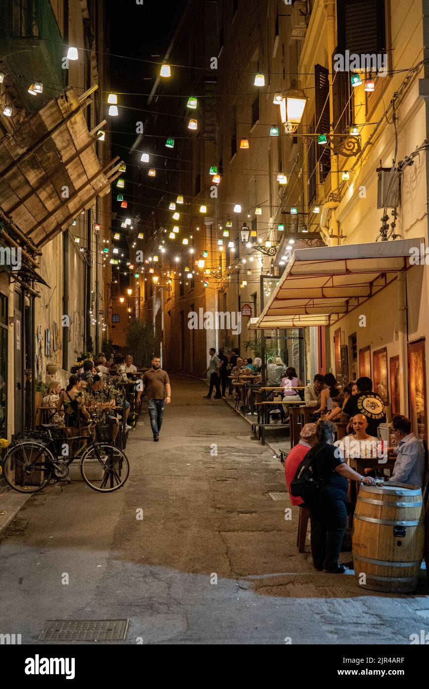 A vertical shot of a street with outdoor cafes and decorative lights in ...