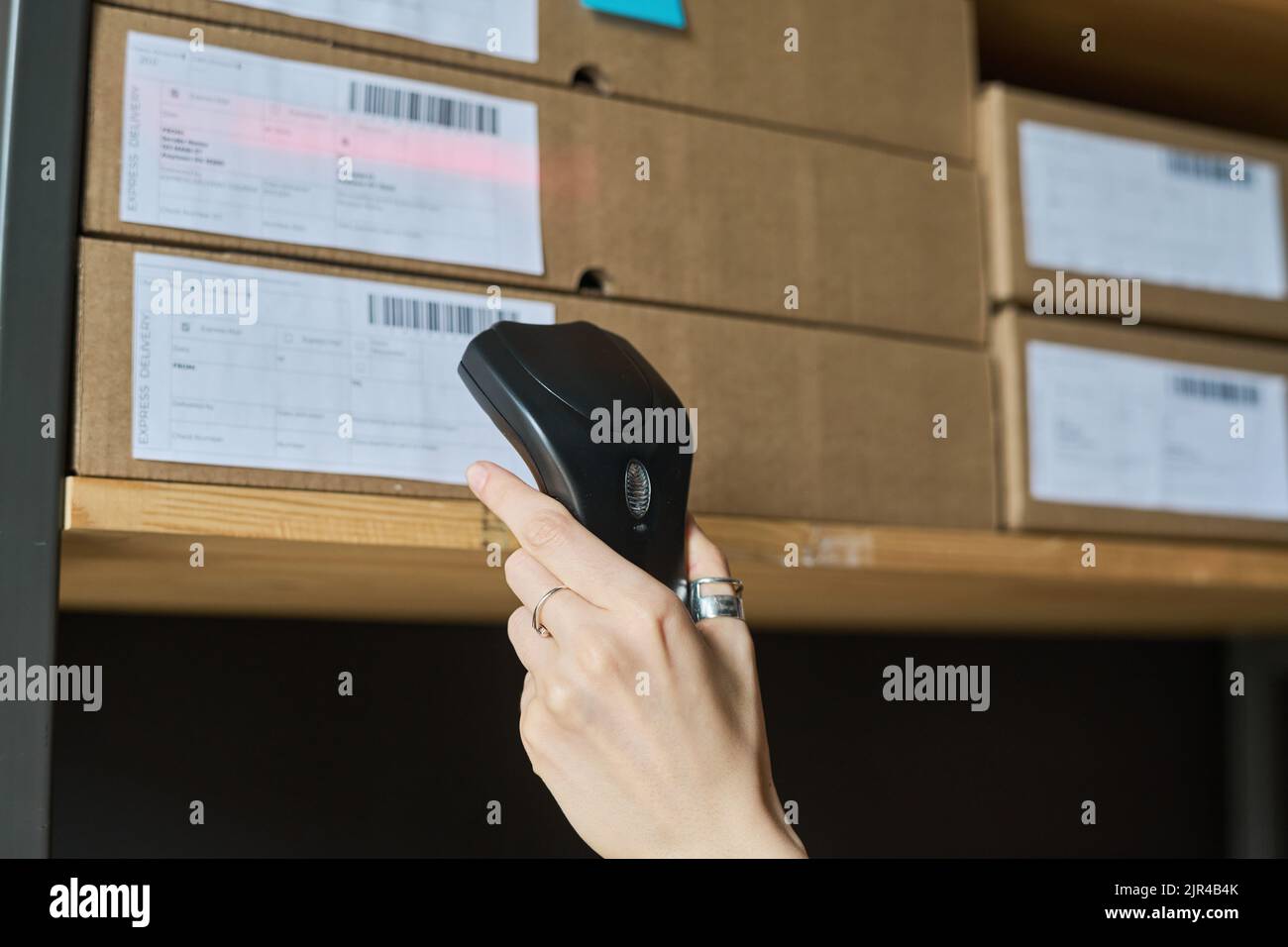 Close-up of woman scanning barcodes on parcels with scanner while ...