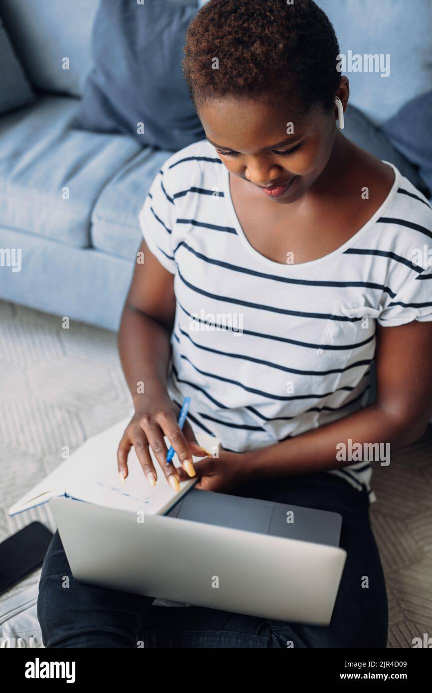 Afro student woman sitting on floor preparing homework or examination ...