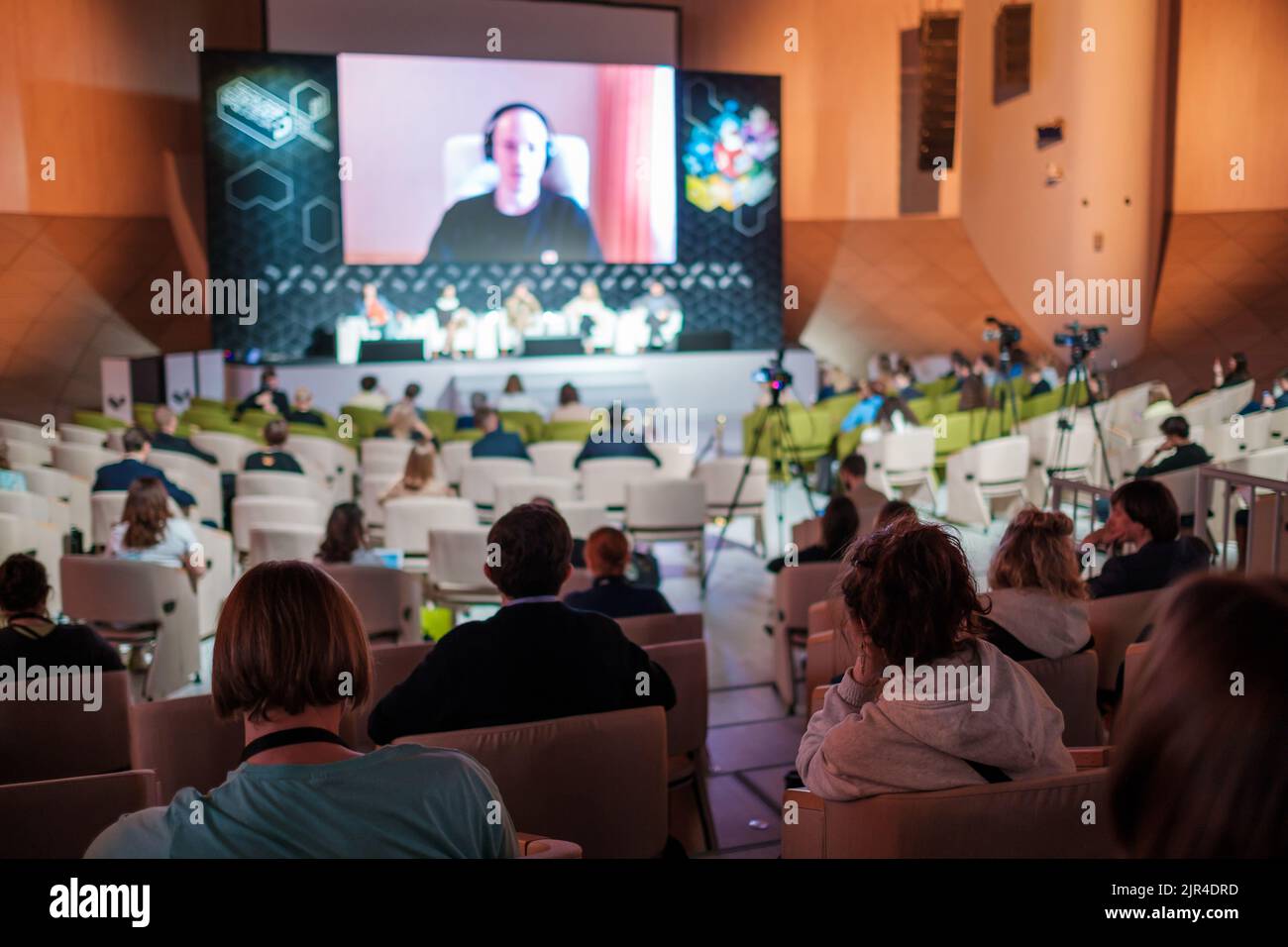 Anonymous people sitting on chairs and listening to woman giving speech ...