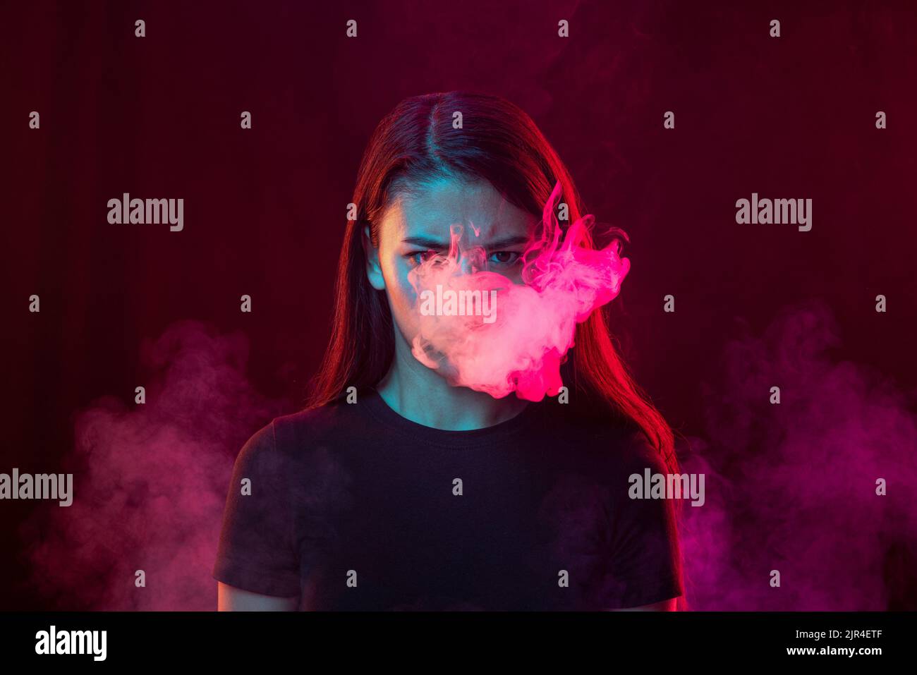Angry young girl with dark hair releases smoke from the mouth isolated ...