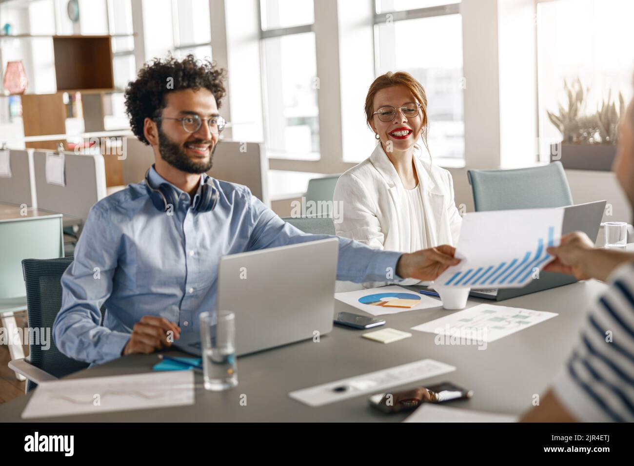 Group of happy diverse coworkers analyzing sales report while working ...