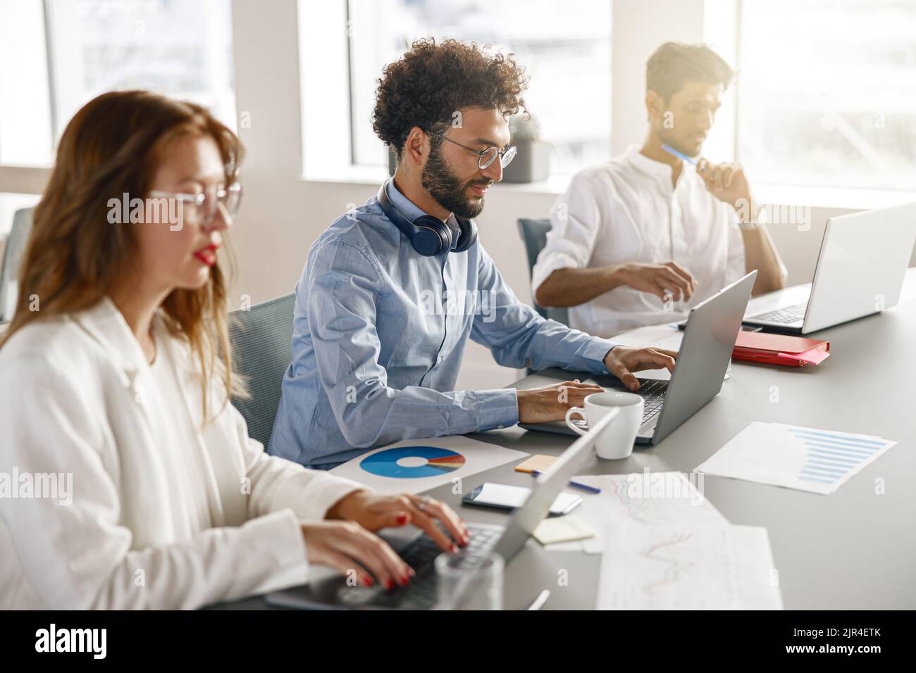 Group of young diverse coworkers analyzing sales report while working ...