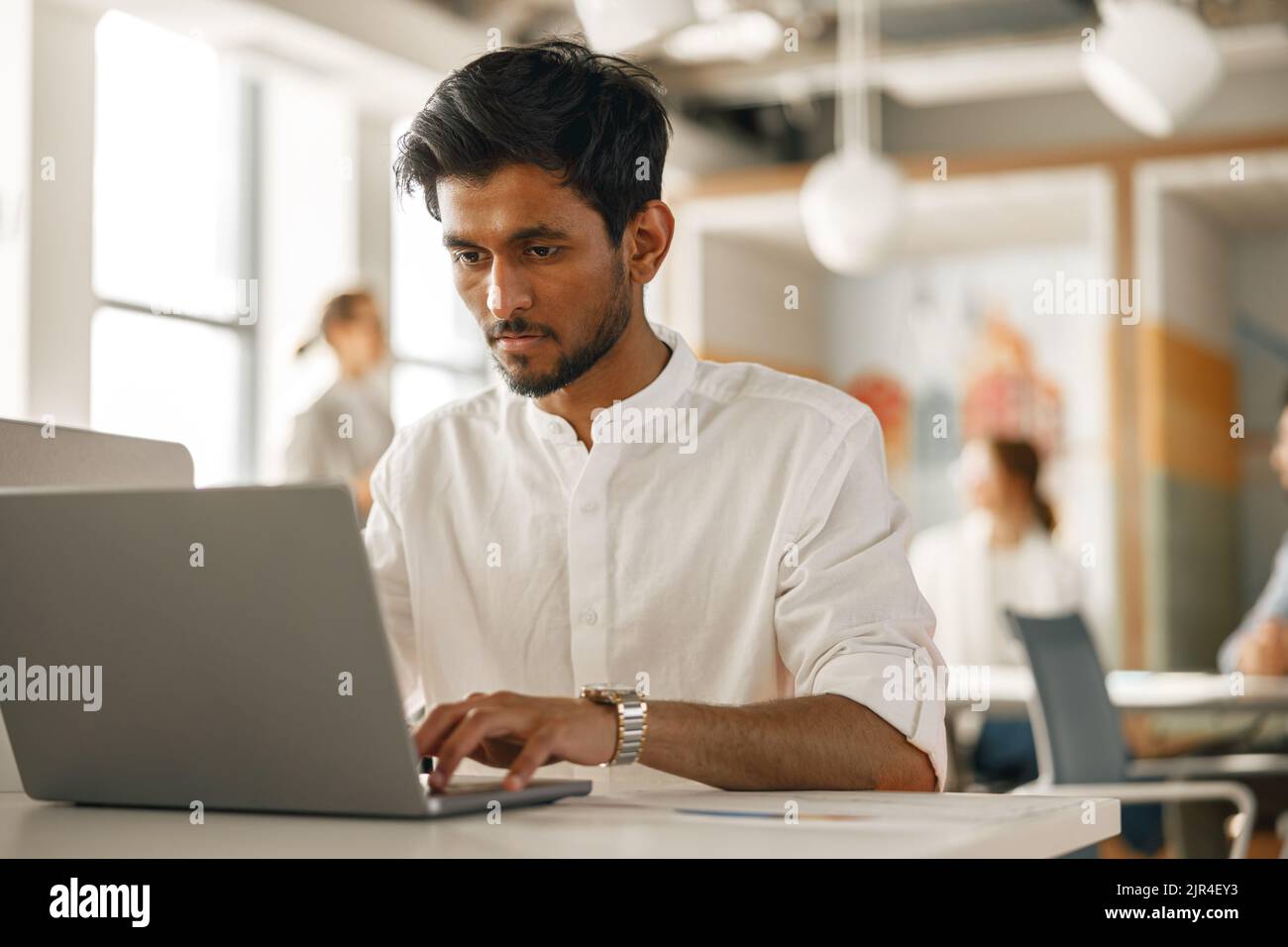Businessman working laptop while sitting in modern office on colleagues ...
